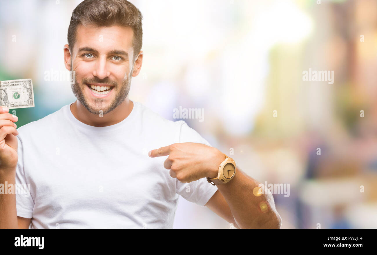 Young handsome man holding dollars over isolated background with ...