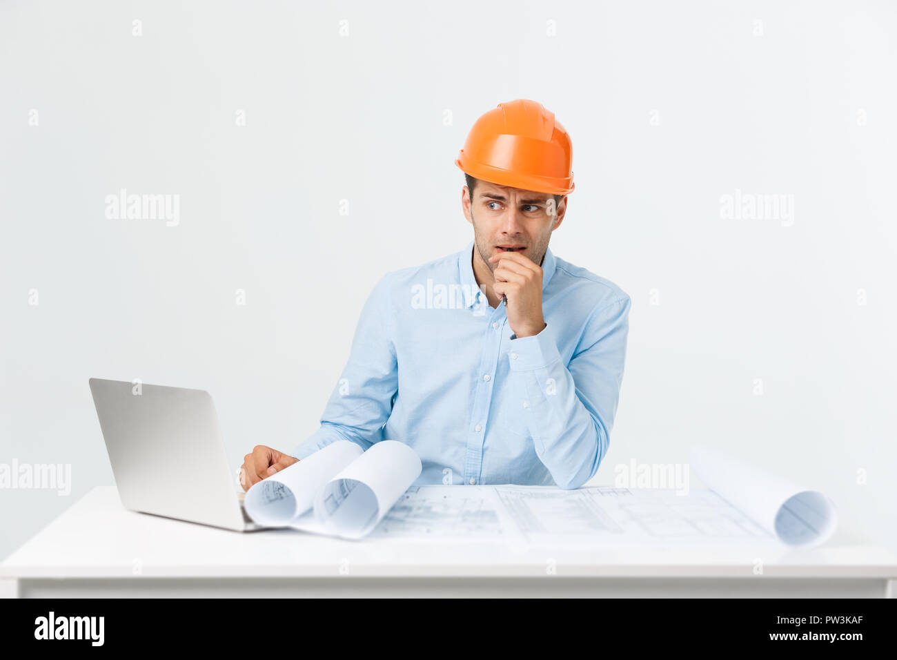 Confident smiling architect in formal wear thinking and working with ...