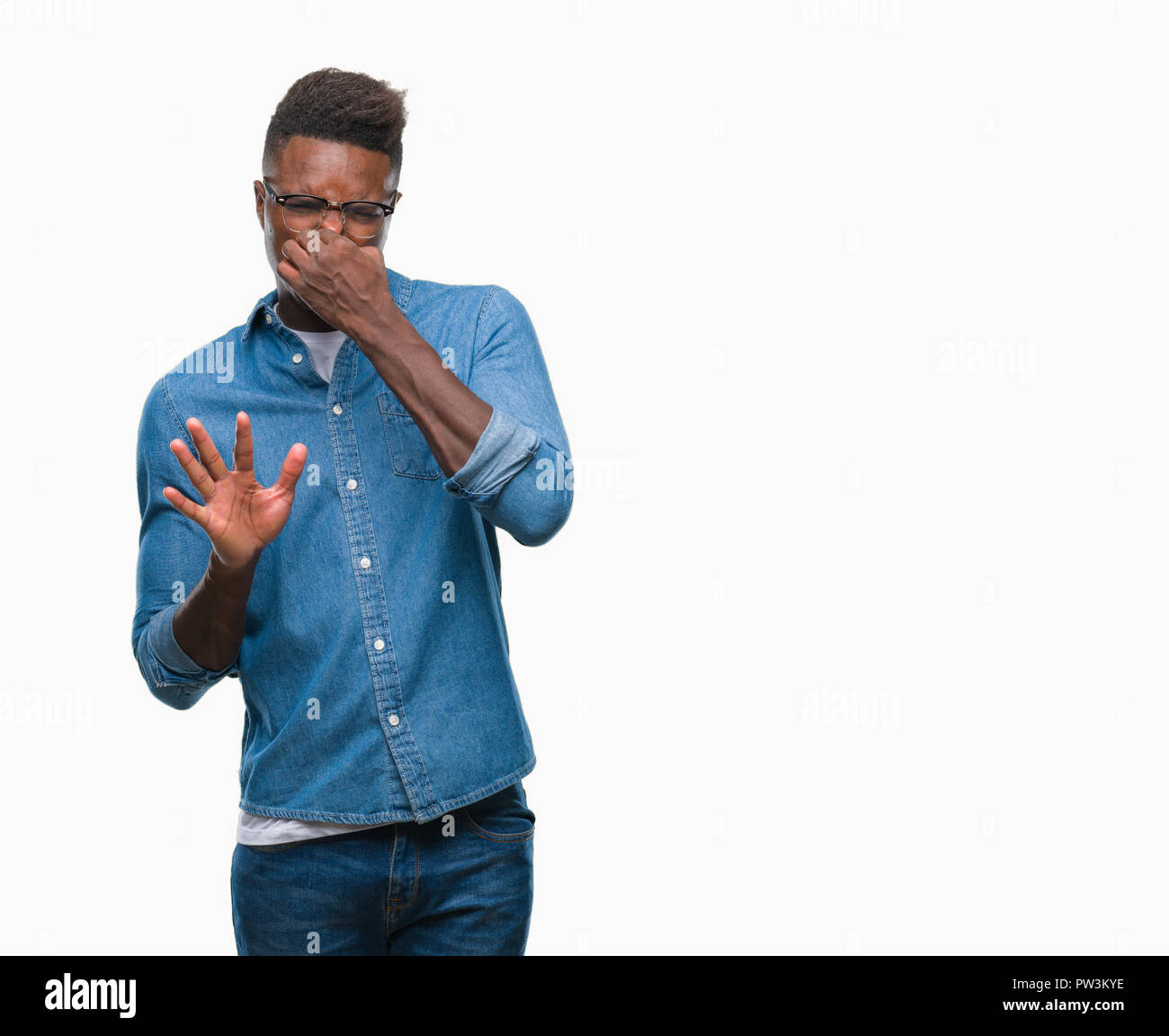 Young african american man over isolated background smelling something ...