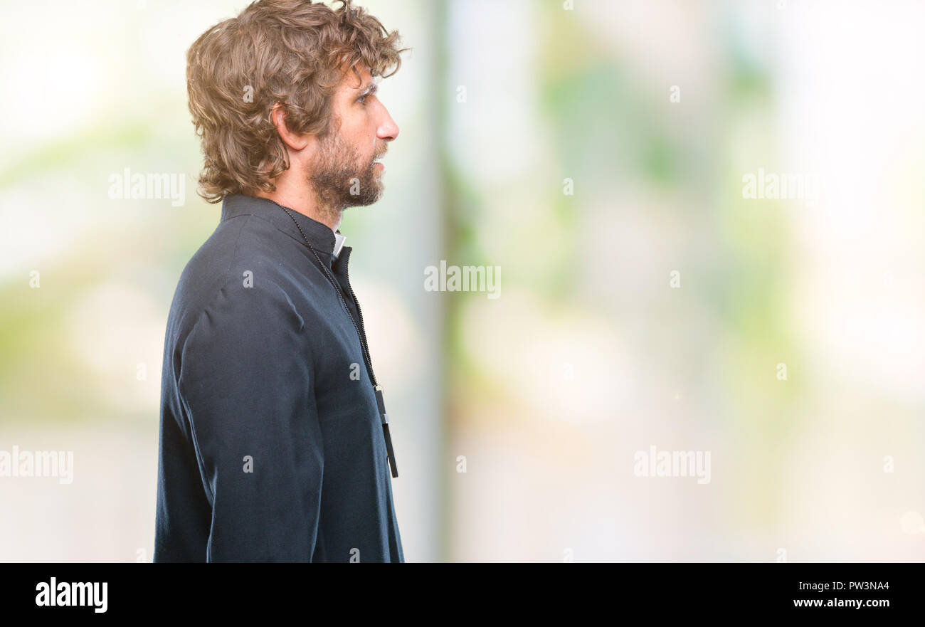 Handsome hispanic catholic priest man over isolated background looking ...
