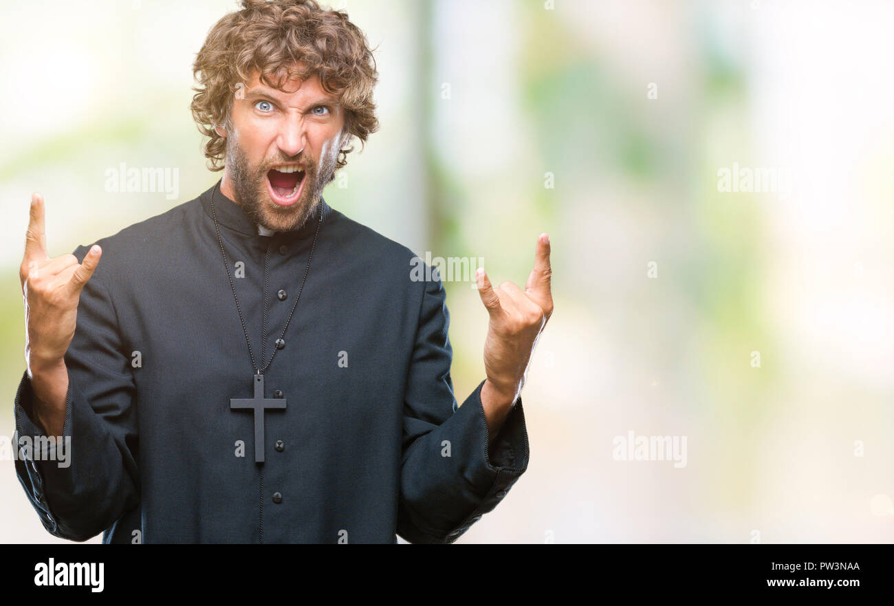 Handsome hispanic catholic priest man over isolated background shouting ...
