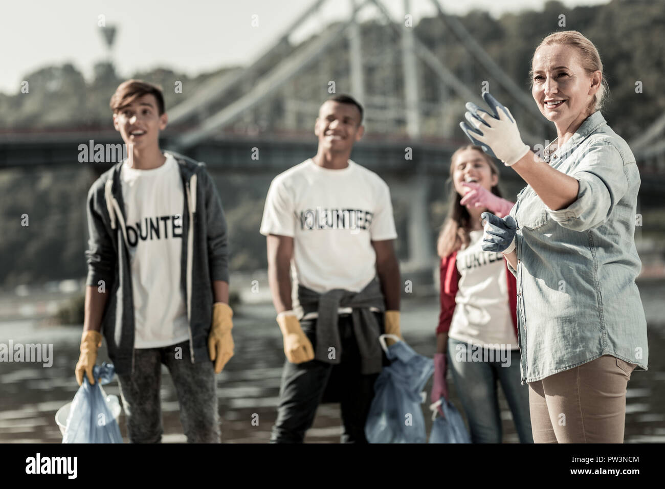 Company of team leader and three young volunteers cleaning up the beach ...
