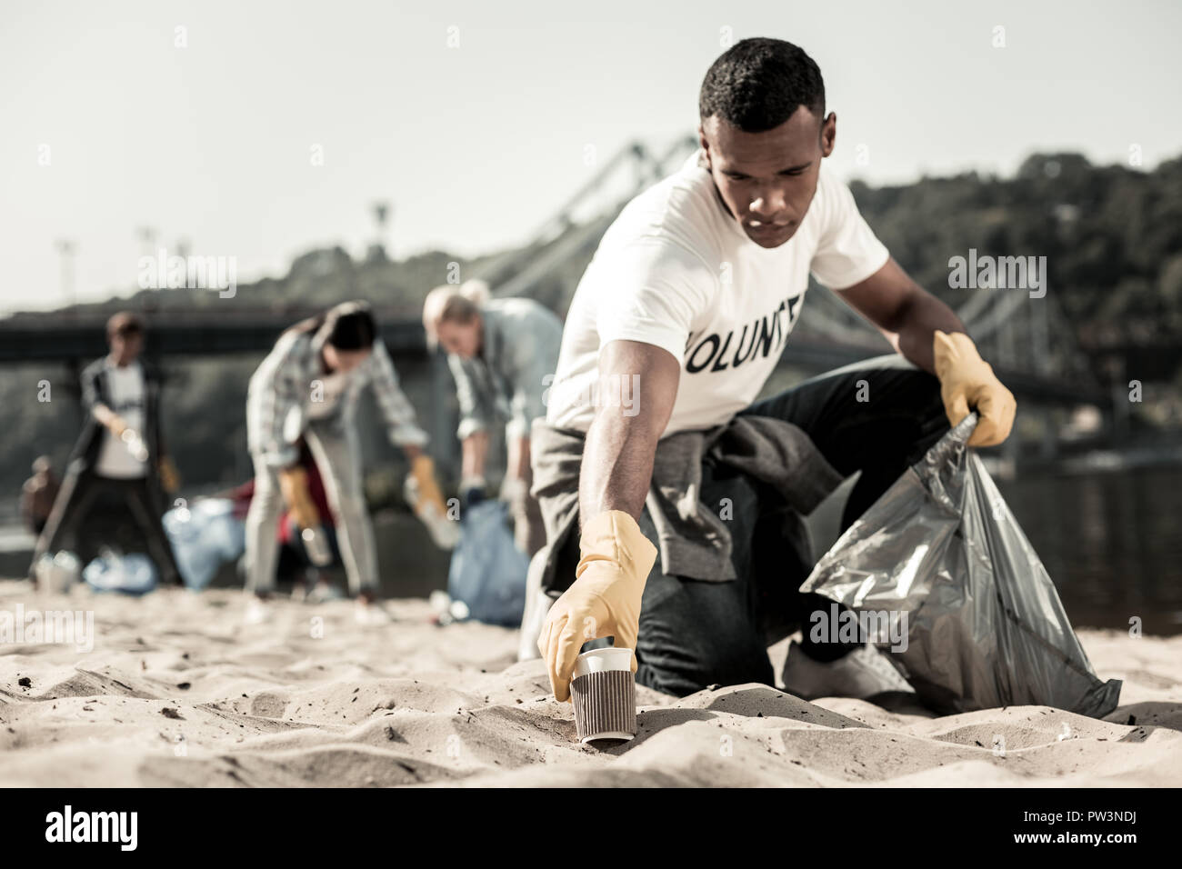 Handsome student enjoying the process of volunteering while cleaning up ...