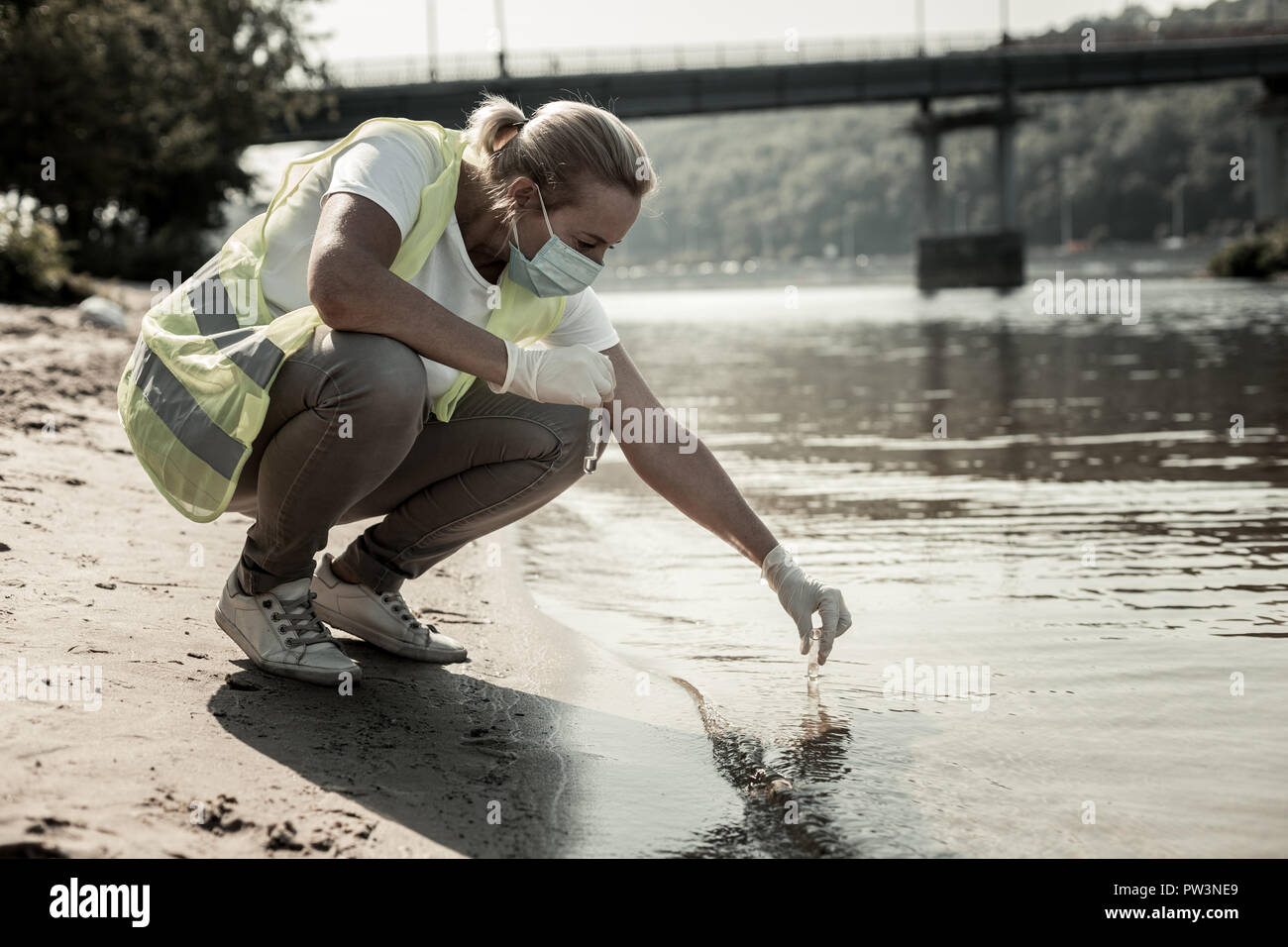 Worker of sanitary inspection service sitting near the river checking ...
