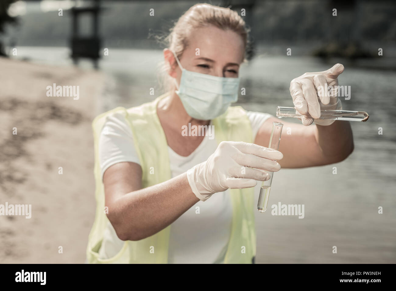Sanitary inspector wearing gloves and mask holding test tubes with ...
