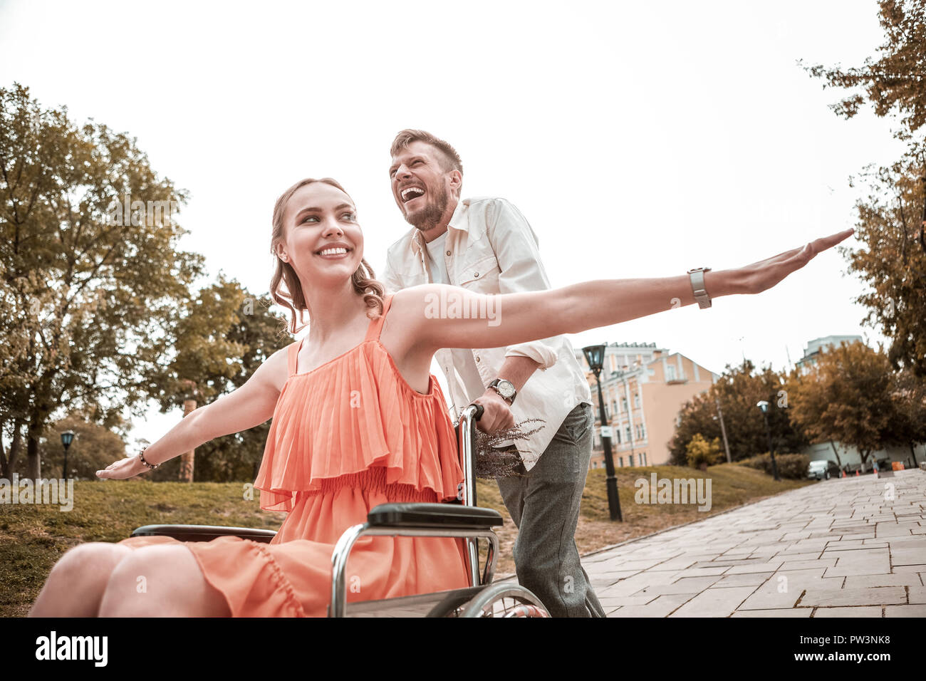 Happy man smiling while riding his disabled girlfriend in the park ...