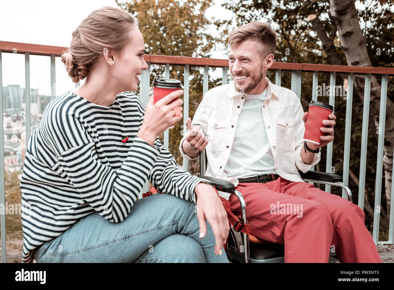 Man in wheelchair laughing while talking to the young woman Stock Photo ...