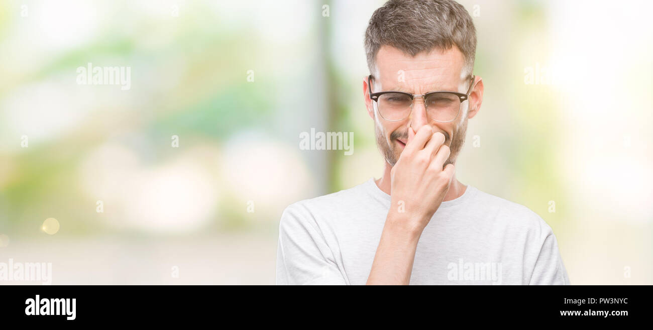 Young tattooed adult man smelling something stinky and disgusting ...