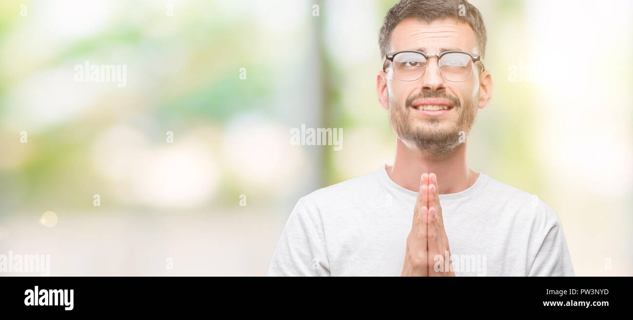 Young tattooed adult man begging and praying with hands together with ...