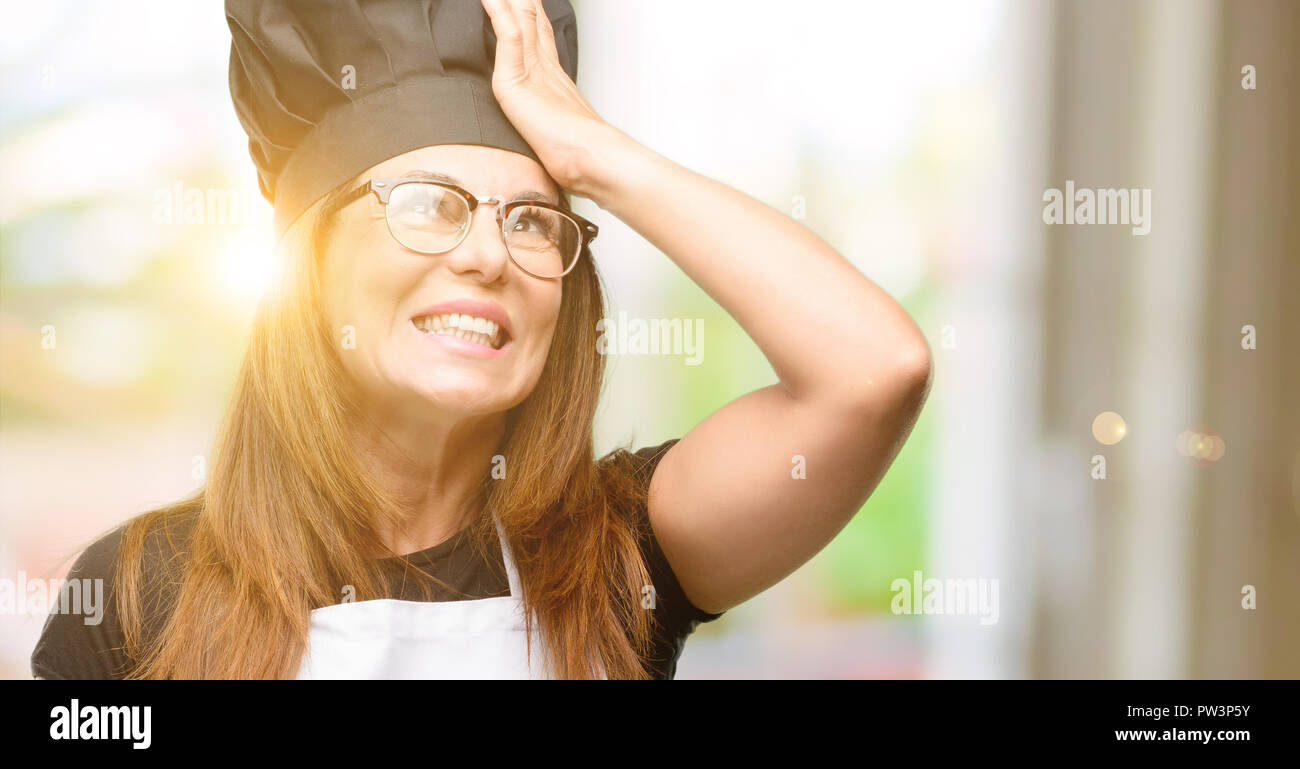 Middle age cook woman wearing chef apron terrified and nervous ...