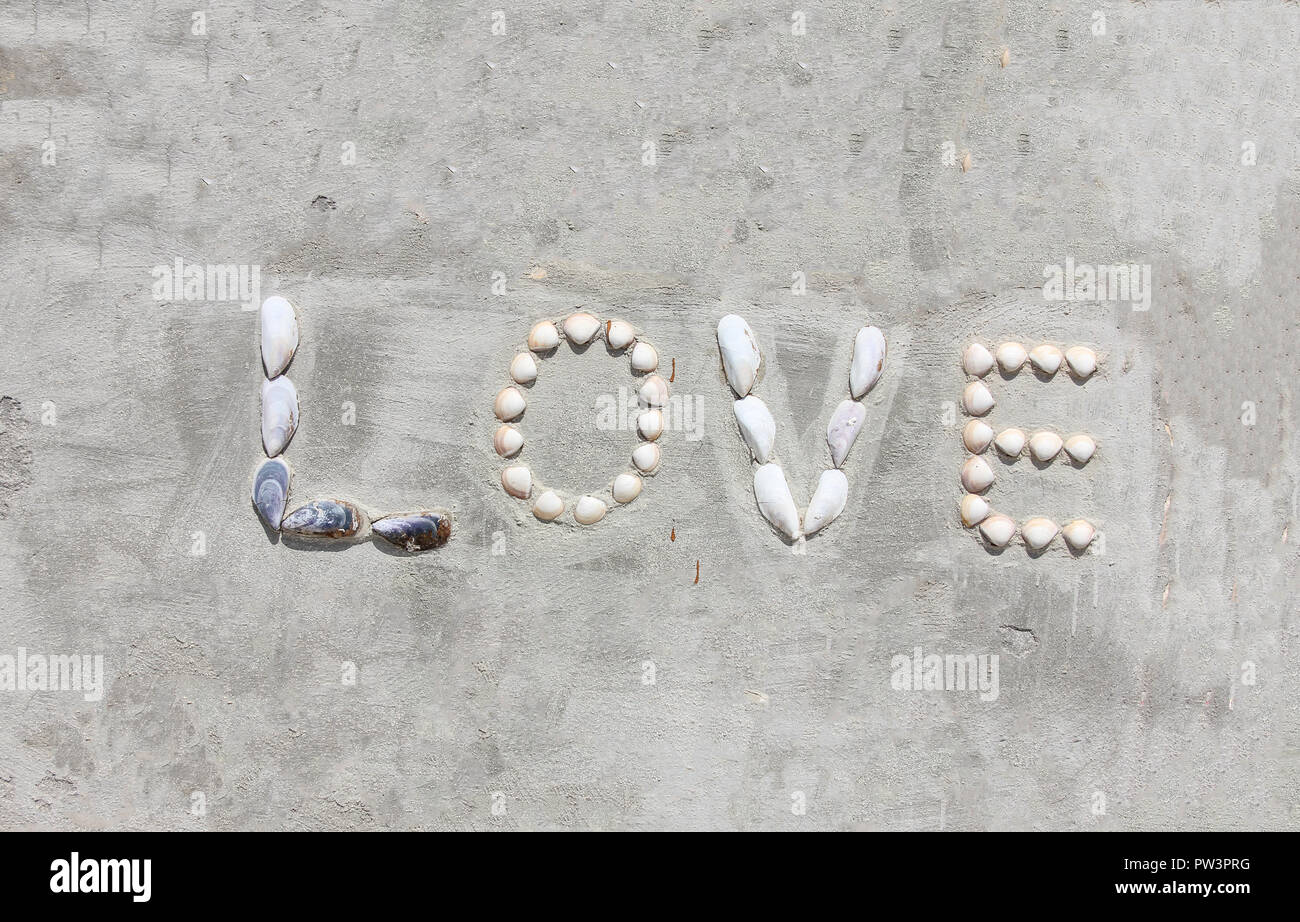 Shell letters make word Love on cement wall background in sunny day ...