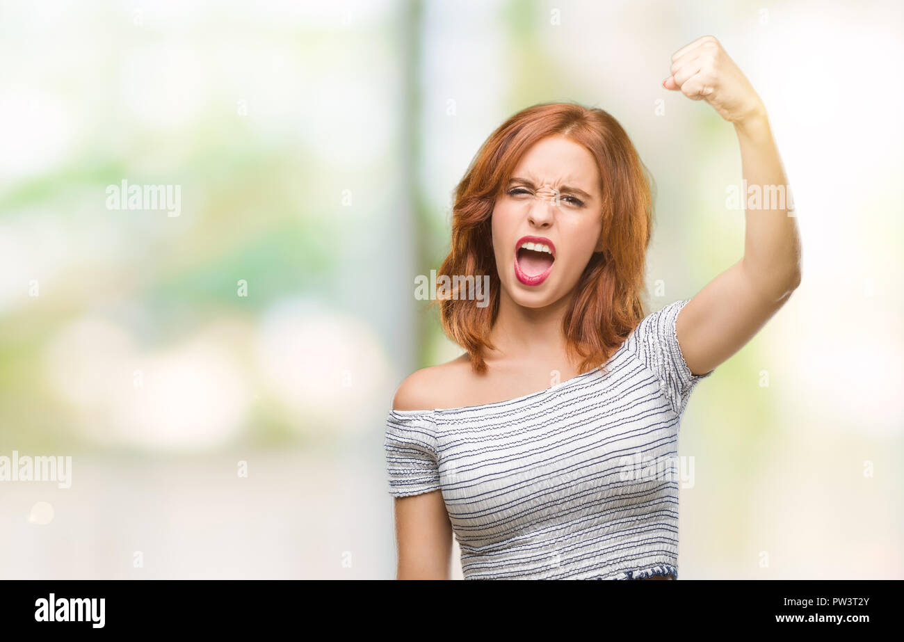 Young beautiful woman over isolated background angry and mad raising ...