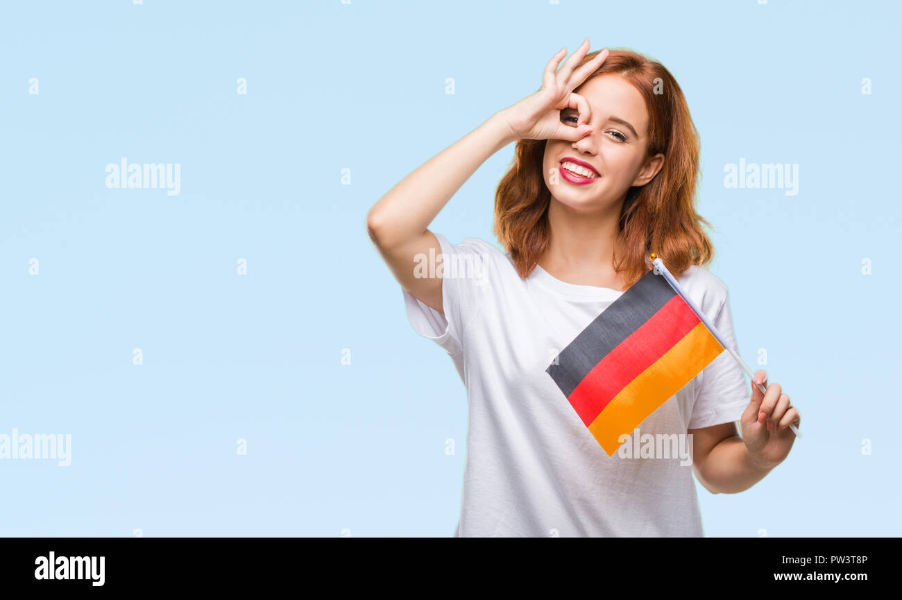 Young beautiful woman holding flag of germany over isolated background ...