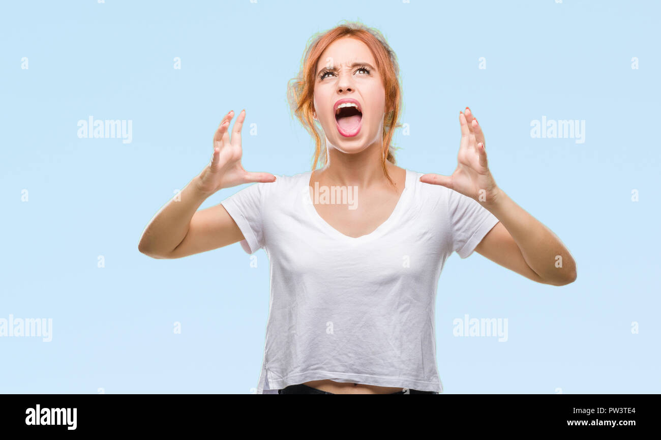 Young beautiful woman over isolated background crazy and mad shouting ...