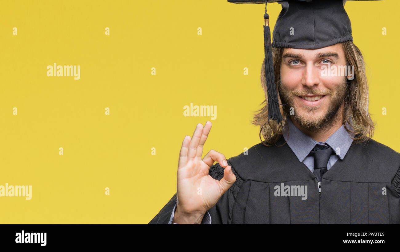 Young handsome graduate man with long hair holding degree over isolated ...