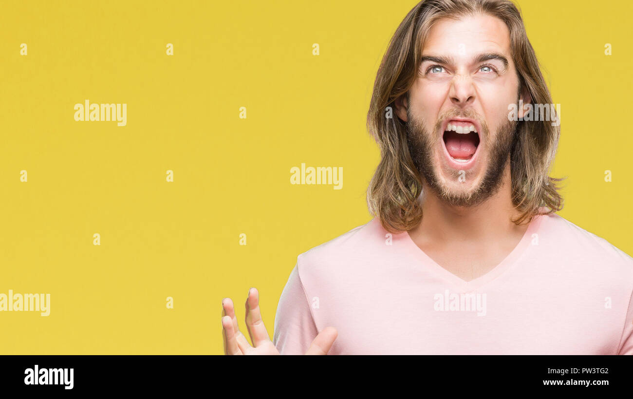 Young handsome man with long hair over isolated background crazy and ...