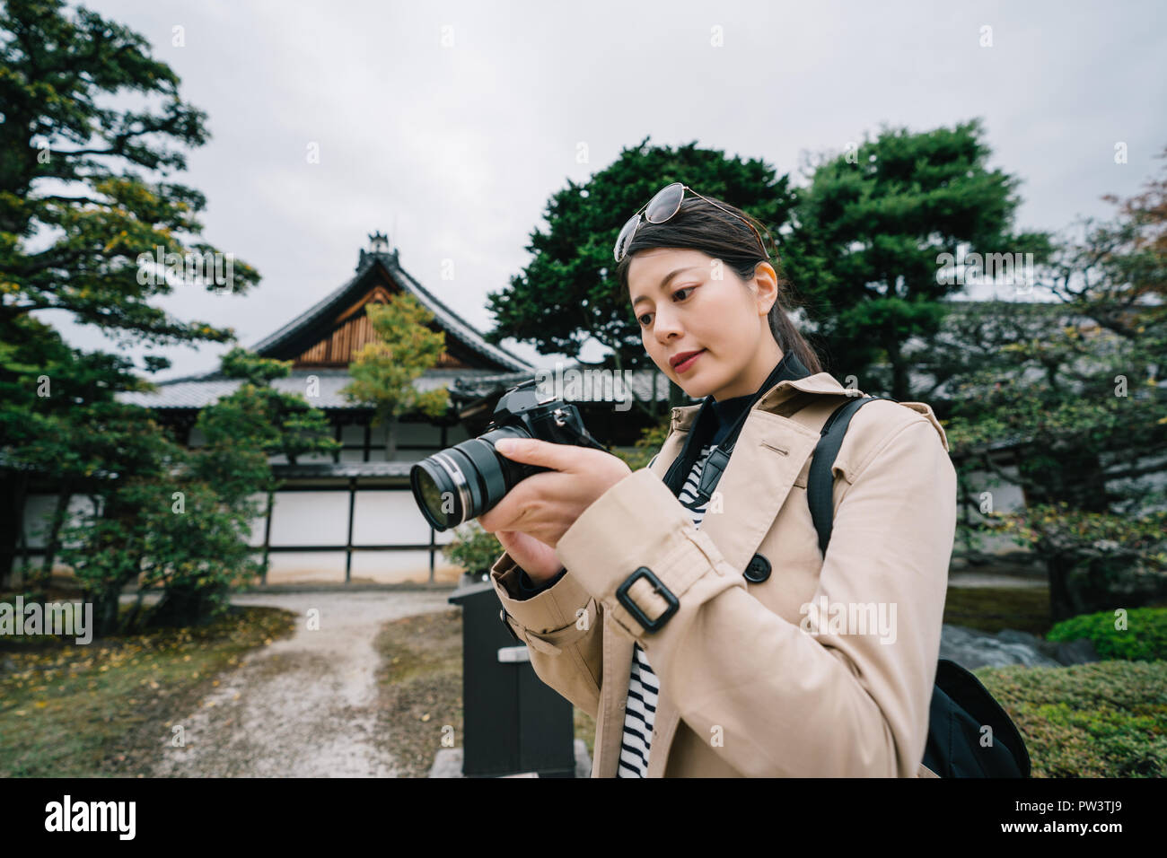 attractive female photographer looking at the photo she took by her slr ...