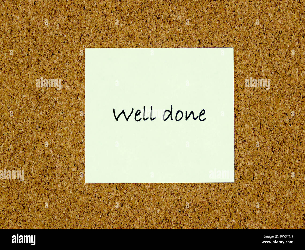 A yellow sticky note with well done written on it on a cork board ...