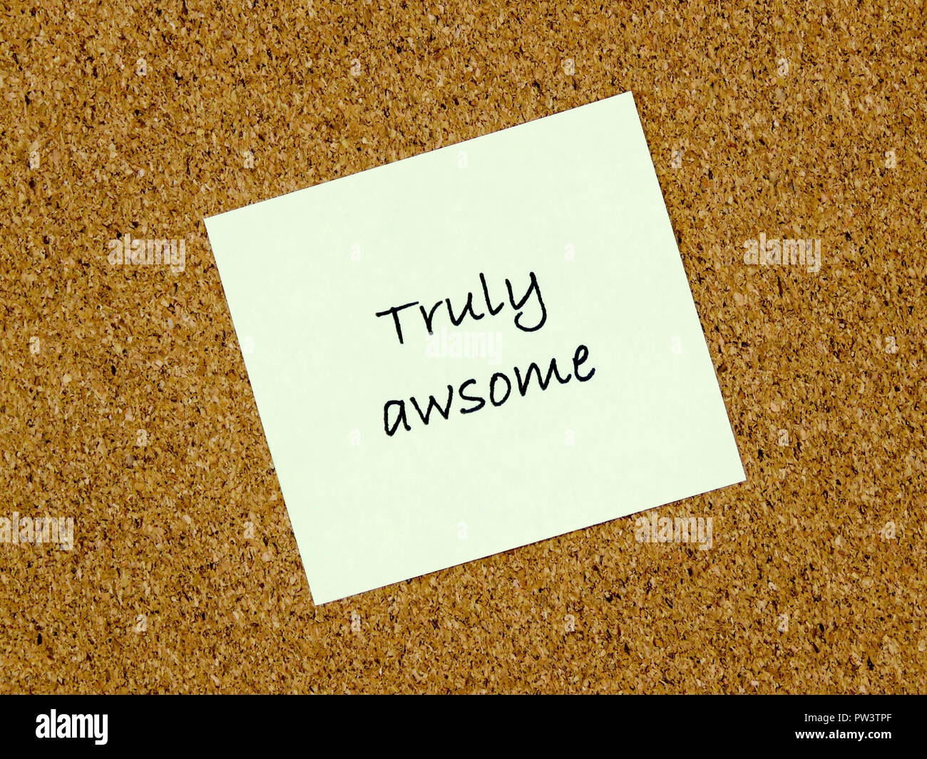 A yellow sticky note with truly awesome written on it on a cork board ...
