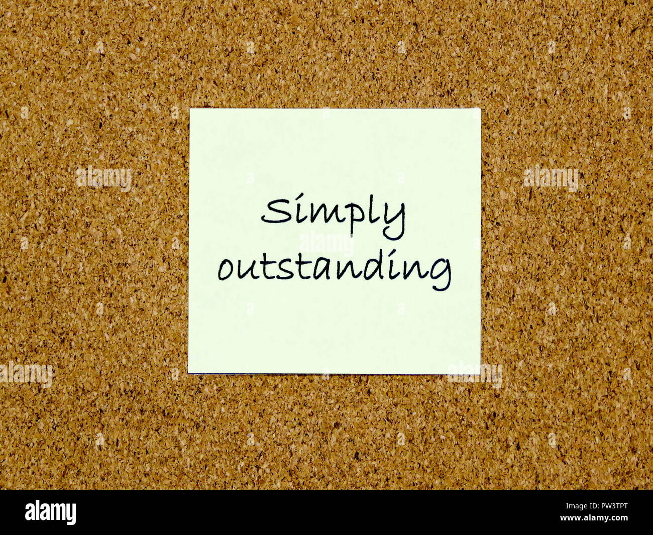 A yellow sticky note with simply outstanding written on it on a cork ...