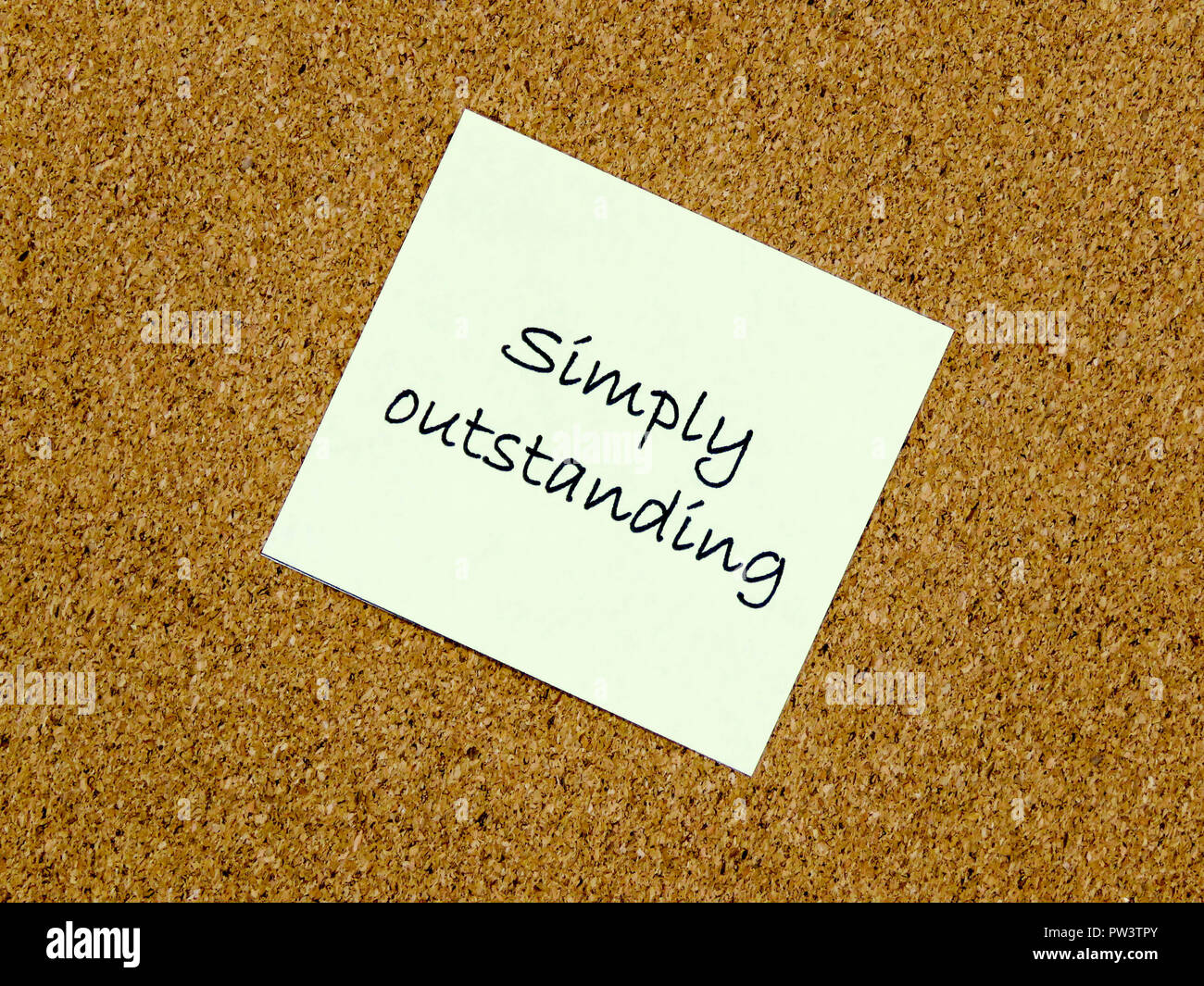 A yellow sticky note with simply outstanding written on it on a cork ...