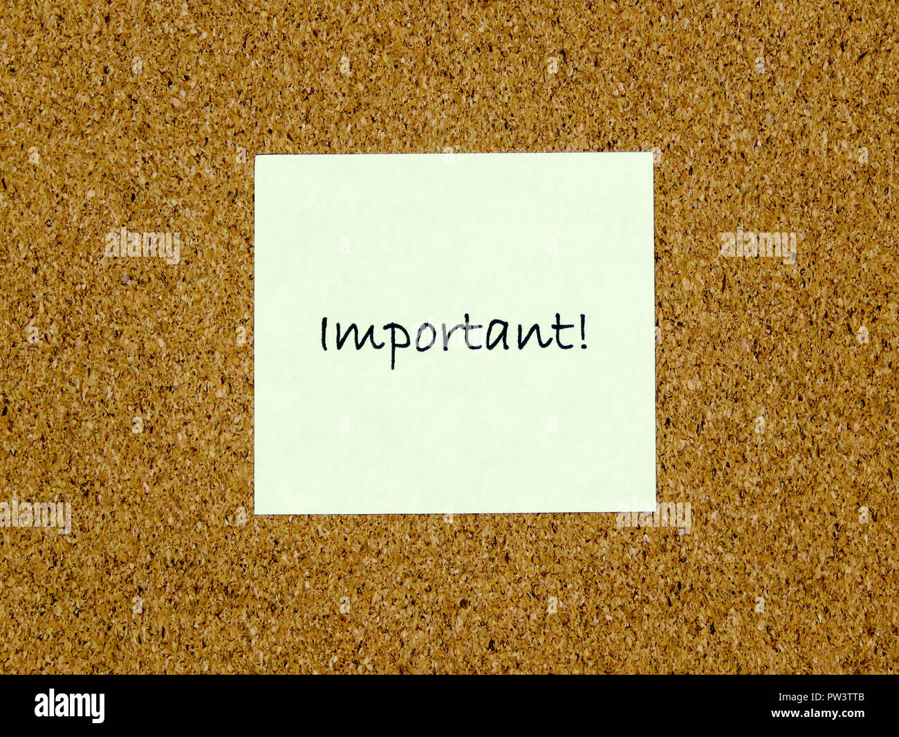 A yellow sticky note with important written on it on a cork board ...