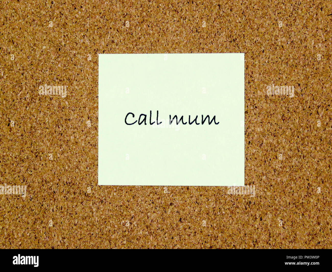 A yellow sticky note with call mum written on it on a cork board ...