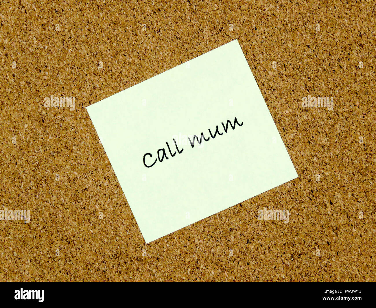 A yellow sticky note with call mum written on it on a cork board ...