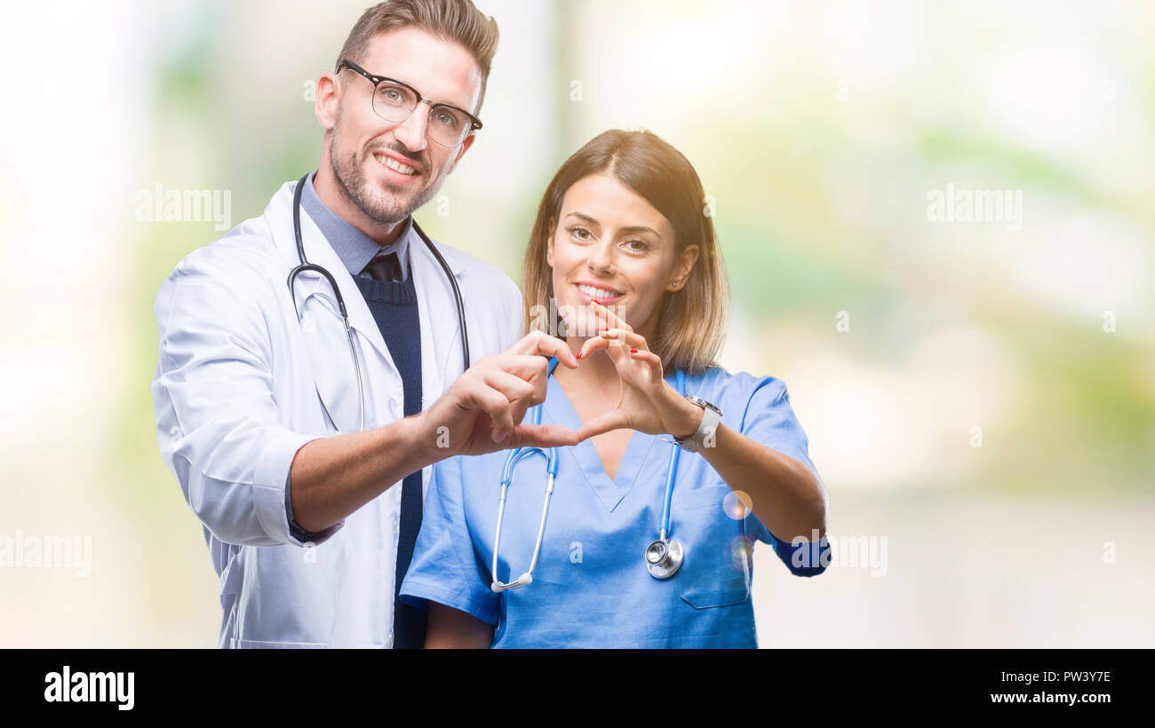 Young couple of doctor and surgeon over isolated background smiling in ...