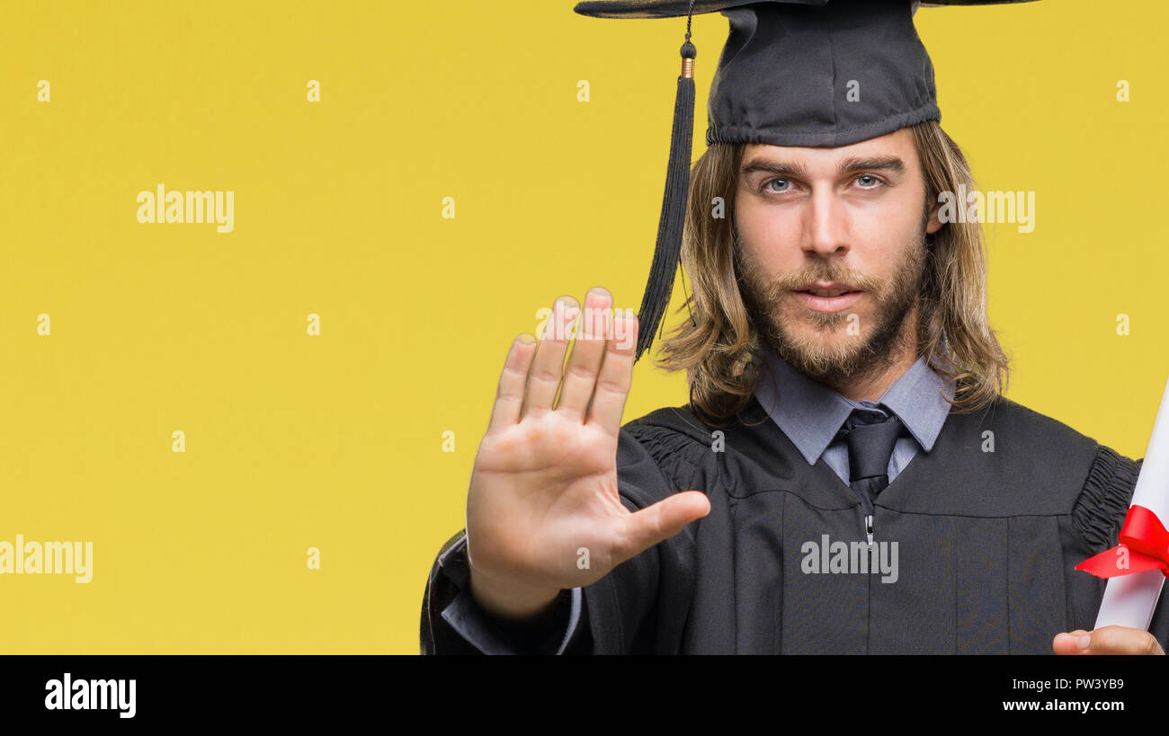 Young handsome graduate man with long hair holding degree over isolated ...