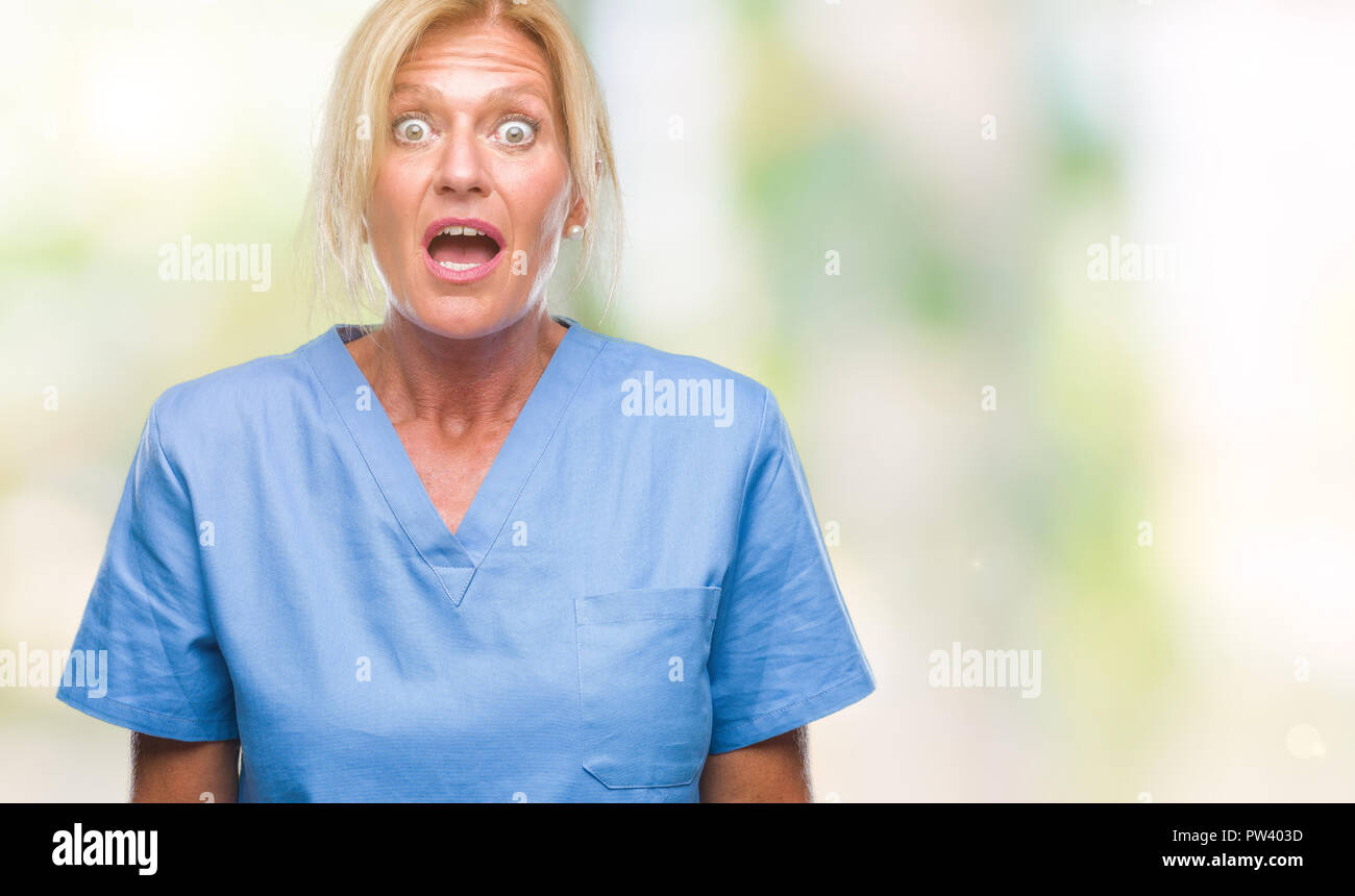 Middle age blonde woman wearing doctor nurse uniform over isolated ...