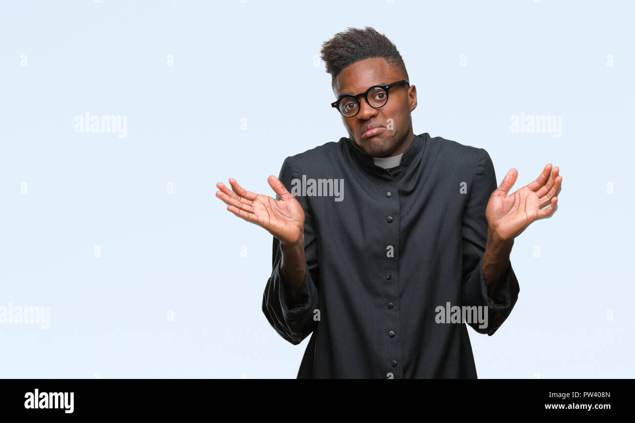 Young african american priest man over isolated background clueless and ...