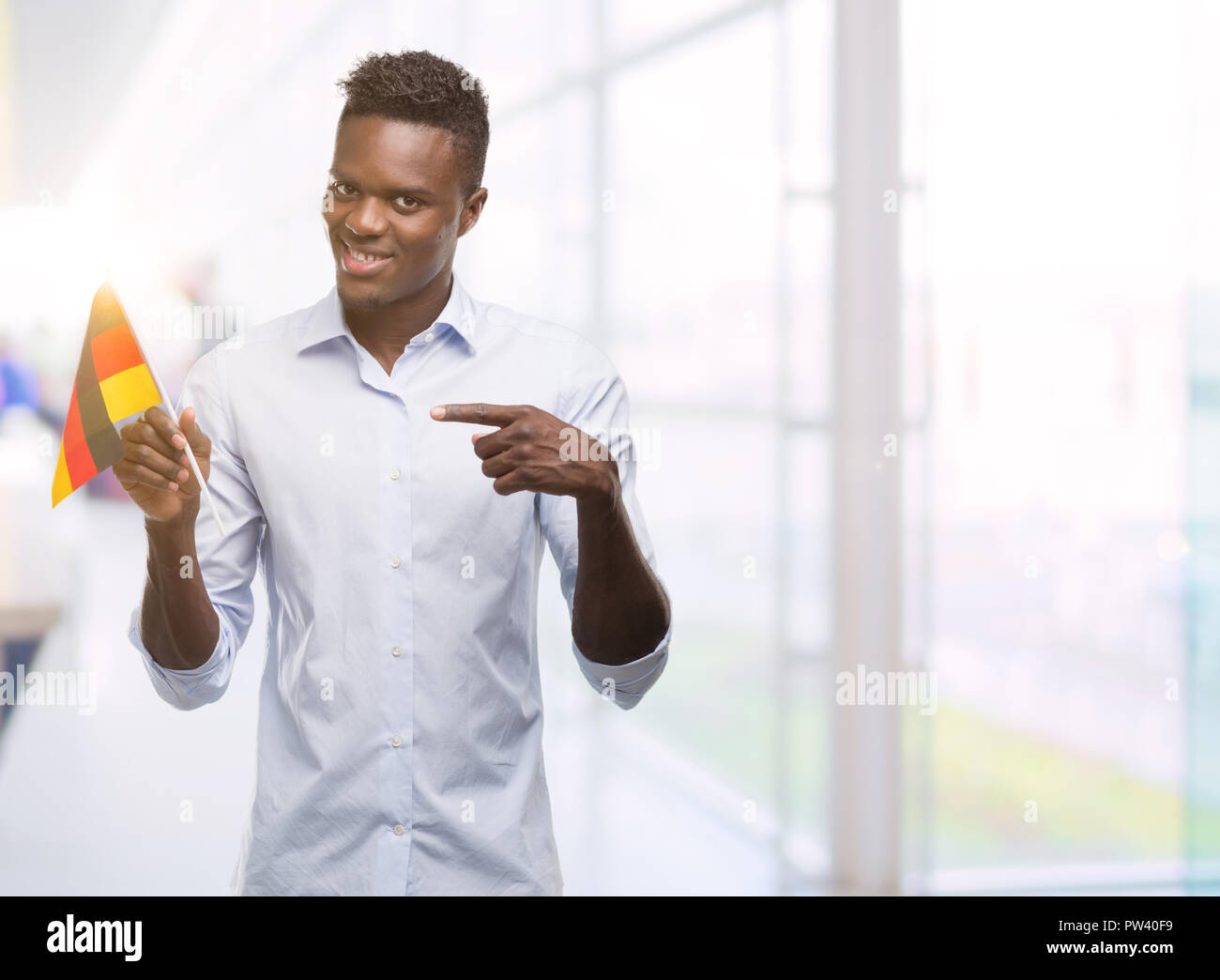Young african american man holding german flag very happy pointing with ...