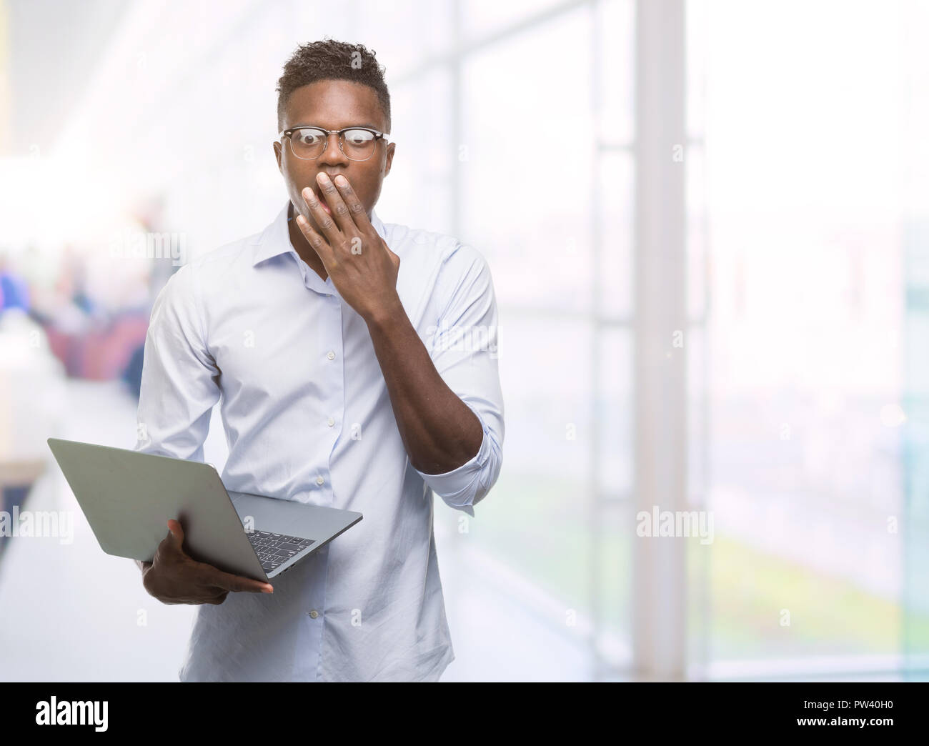 Young african american businessman using computer laptop cover mouth ...