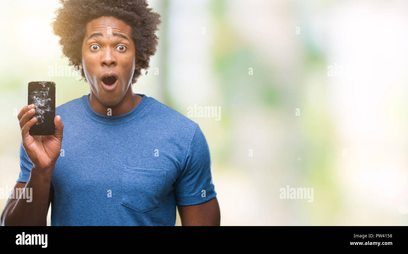 Afro american man holding broken smartphone over isolated background ...