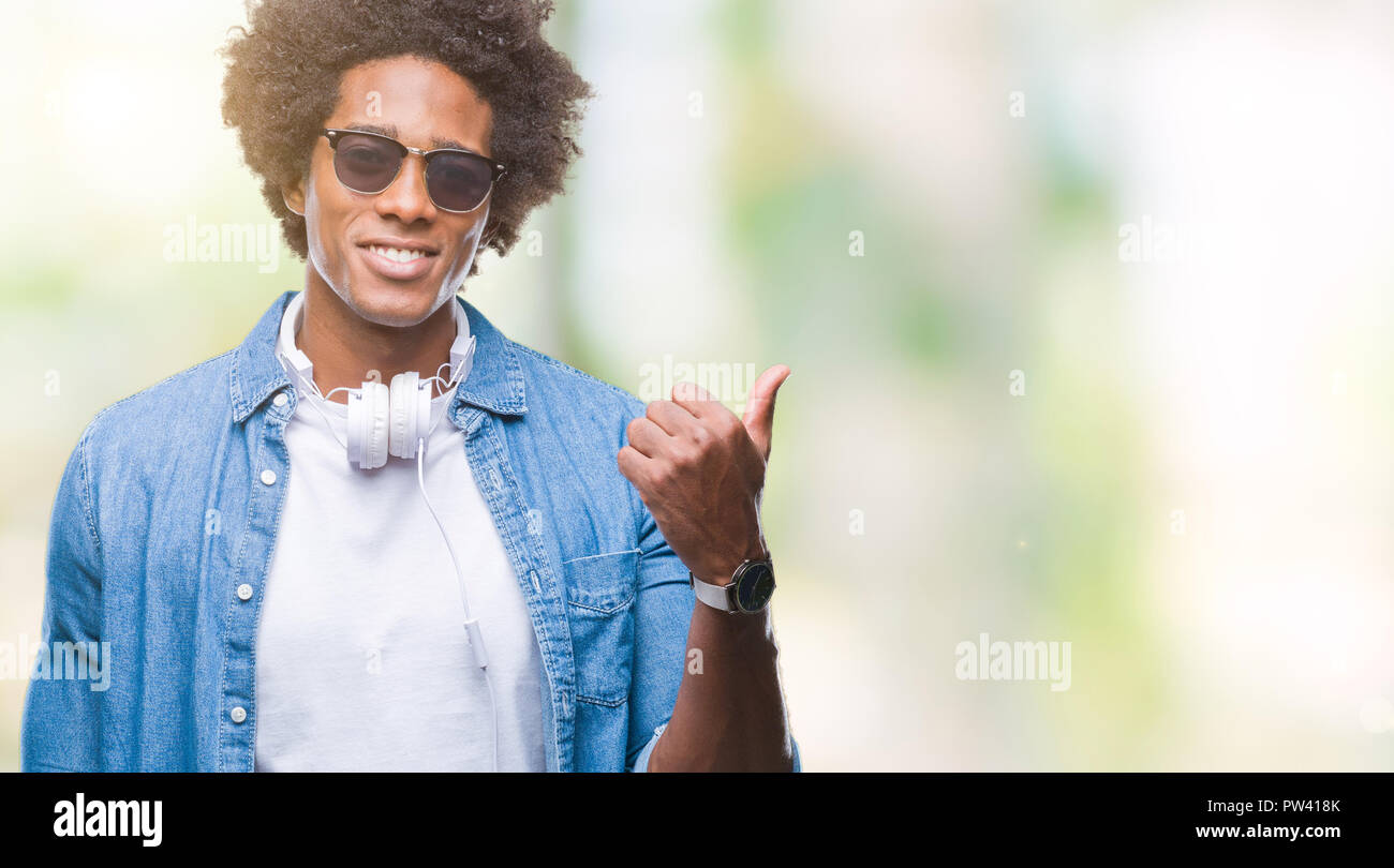 Afro american man wearing headphones listening to music over isolated background smiling with ...