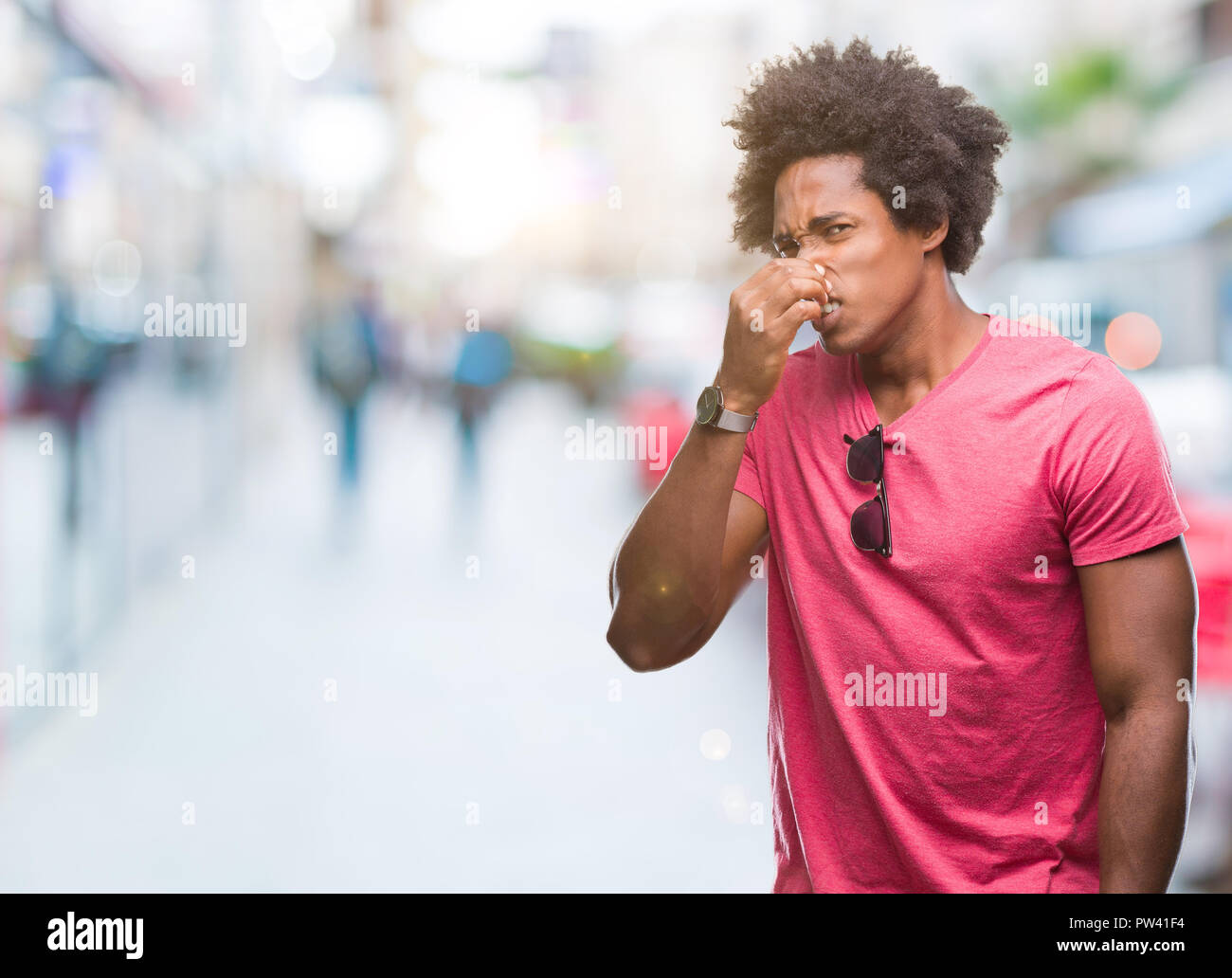 Afro american man over isolated background smelling something stinky ...
