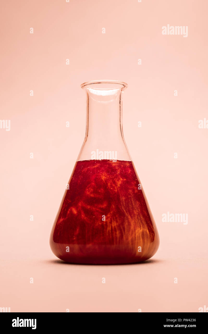 Erlenmeyer flask over light orange background Stock Photo - Alamy