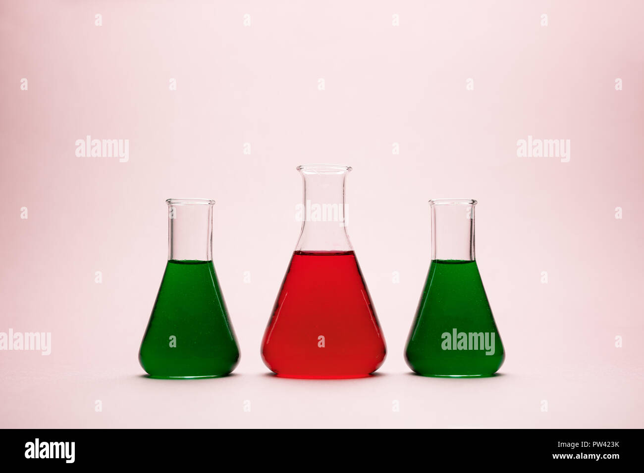 Three erlenmeyer flasks over light pink background Stock Photo - Alamy
