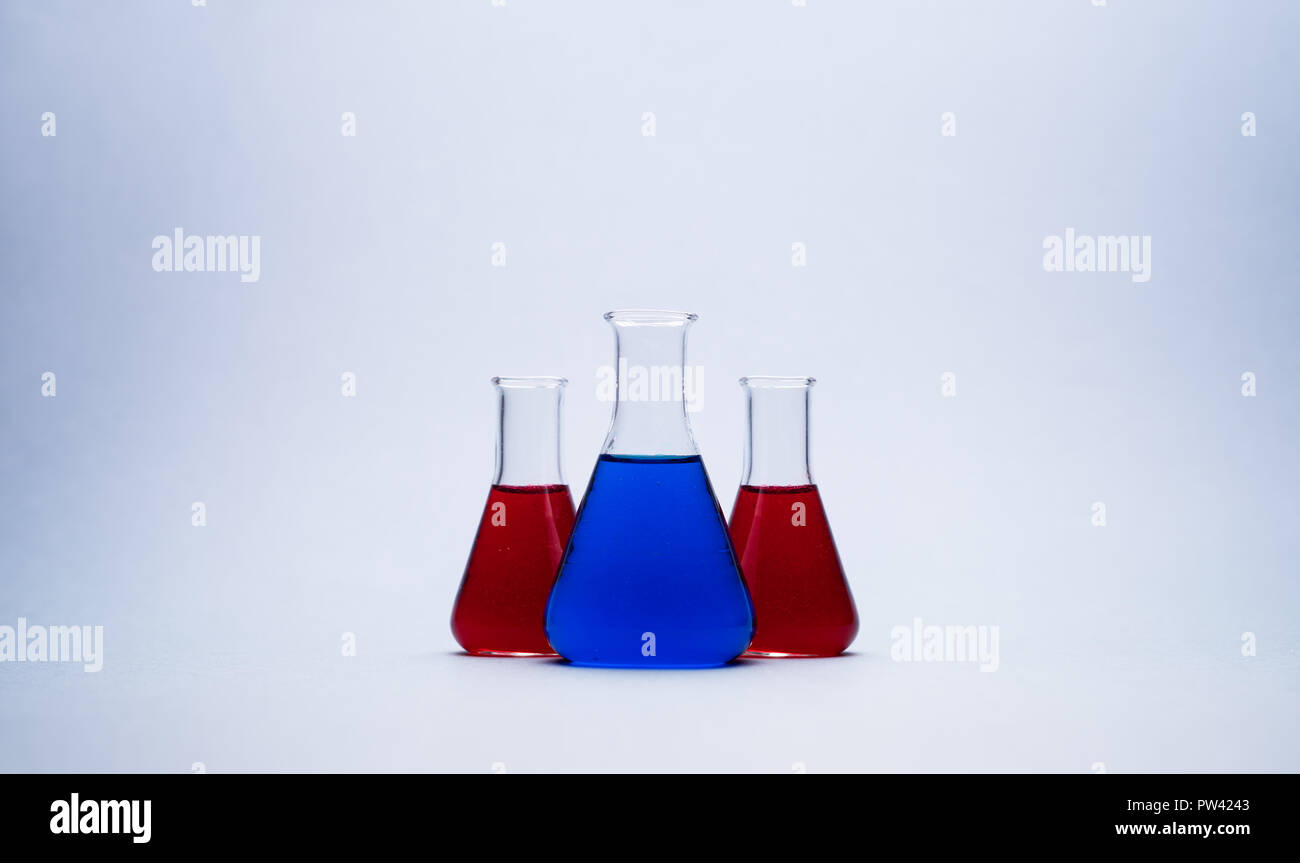 Three erlenmeyer flasks over colorful background Stock Photo - Alamy