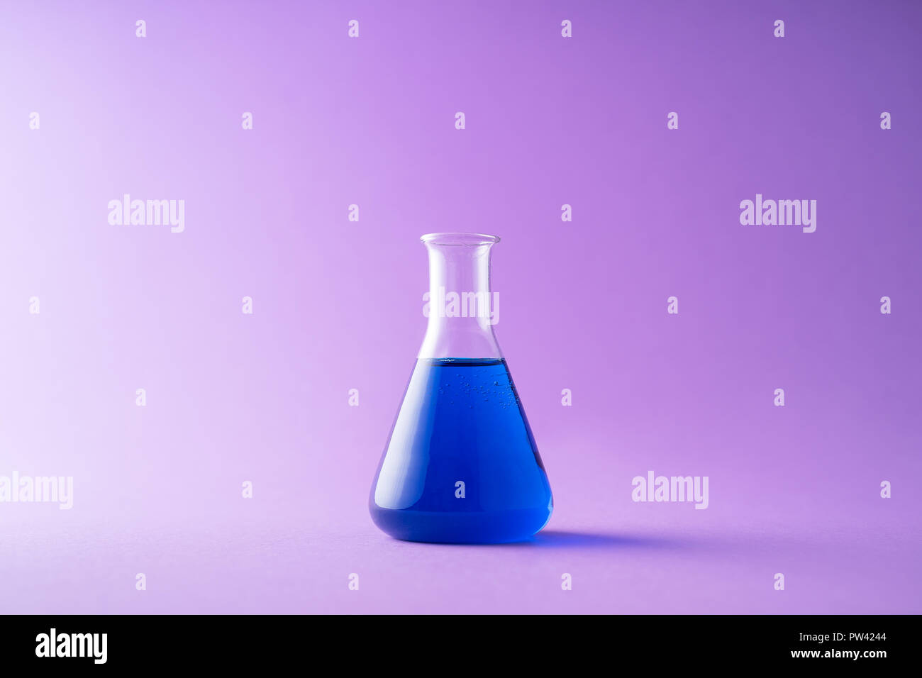 Erlenmeyer flask over purple background Stock Photo - Alamy