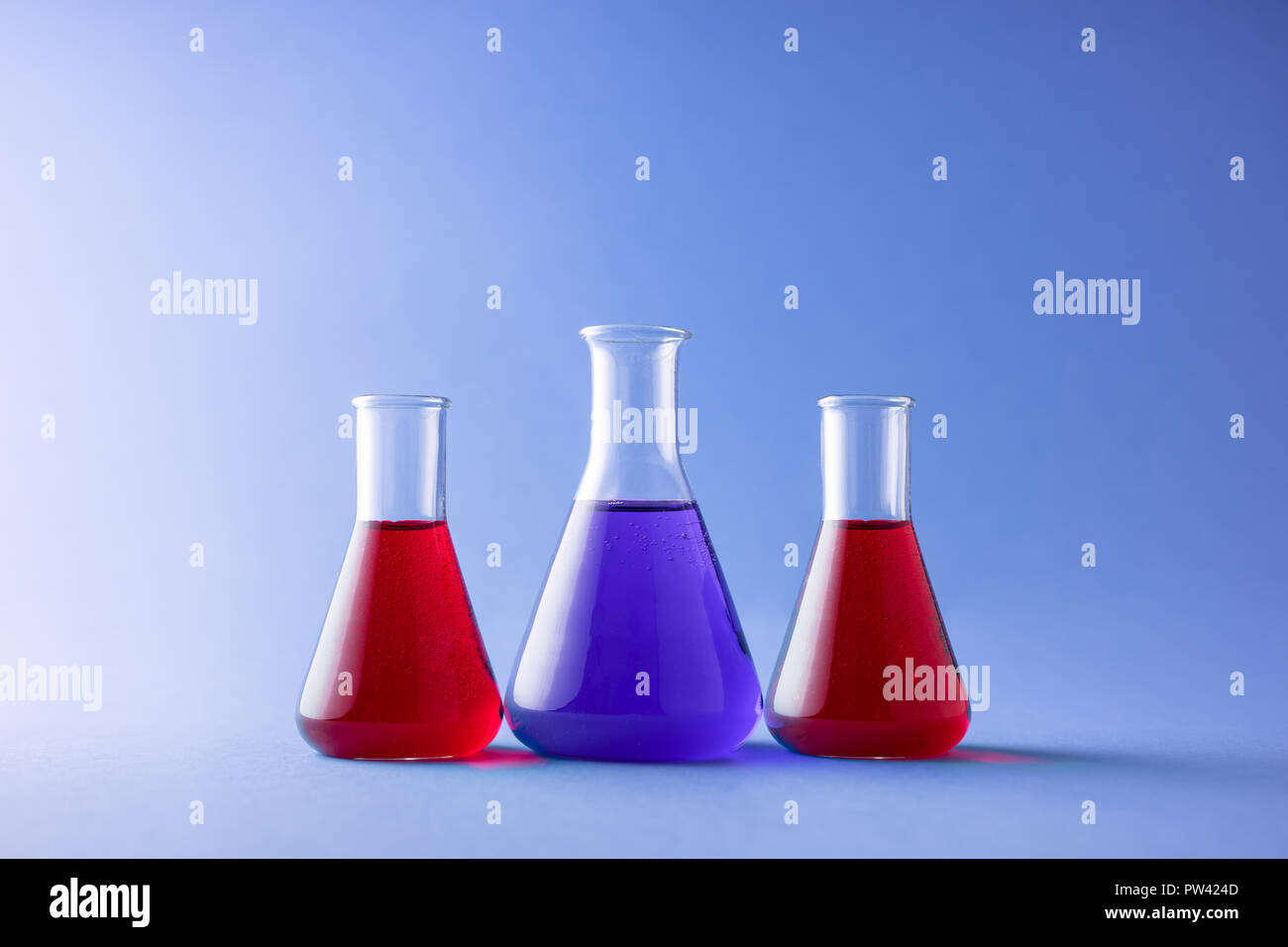 Three erlenmeyer flasks over colorful background Stock Photo - Alamy