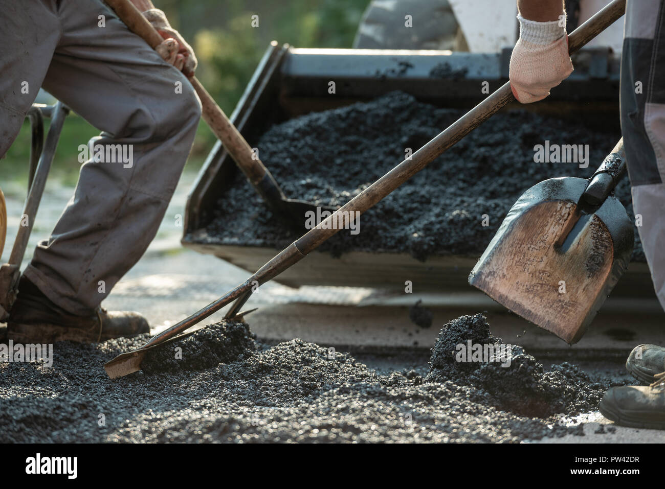 Workers applying gravel and cement to a bump in the road to make new ...