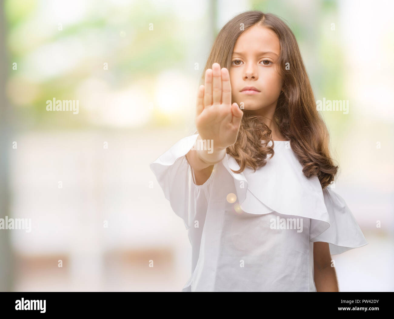 Brunette hispanic girl doing stop sing with palm of the hand. Warning ...