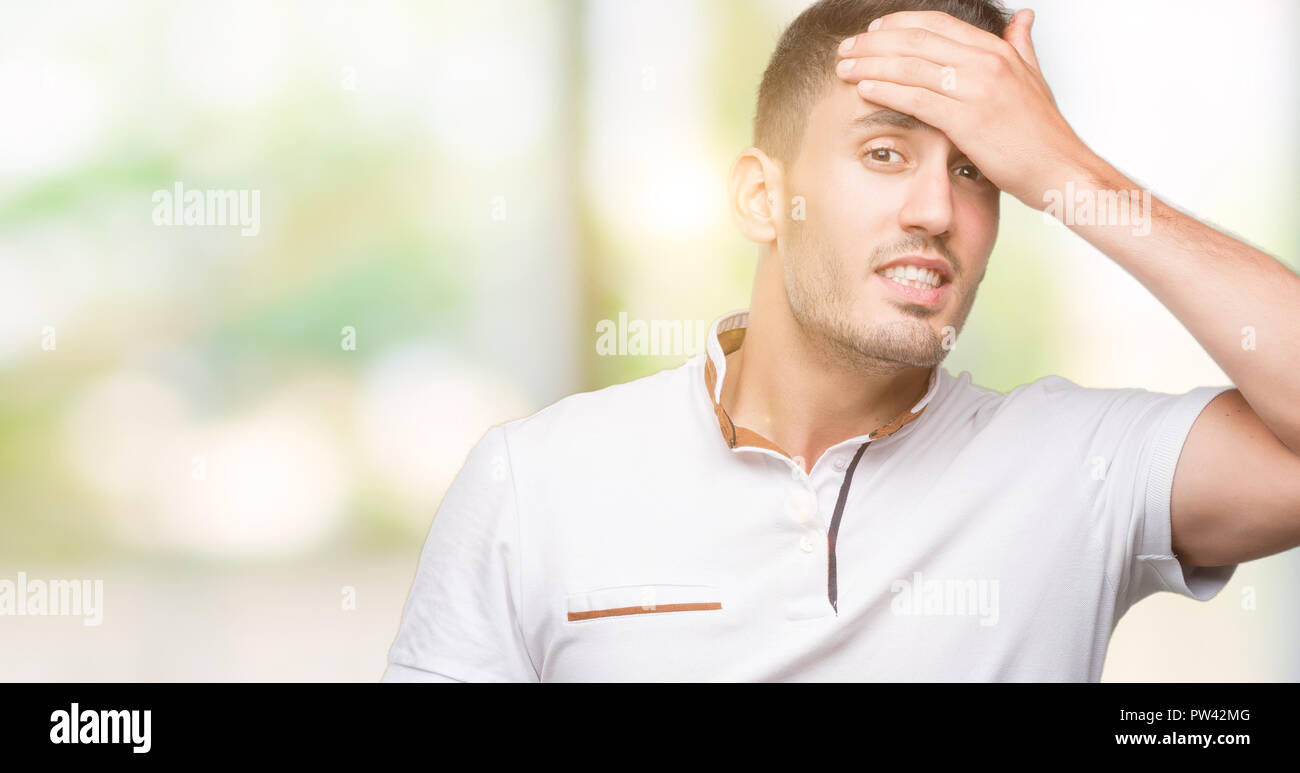 Handsome young casual man wearing white t-shirt stressed with hand on ...