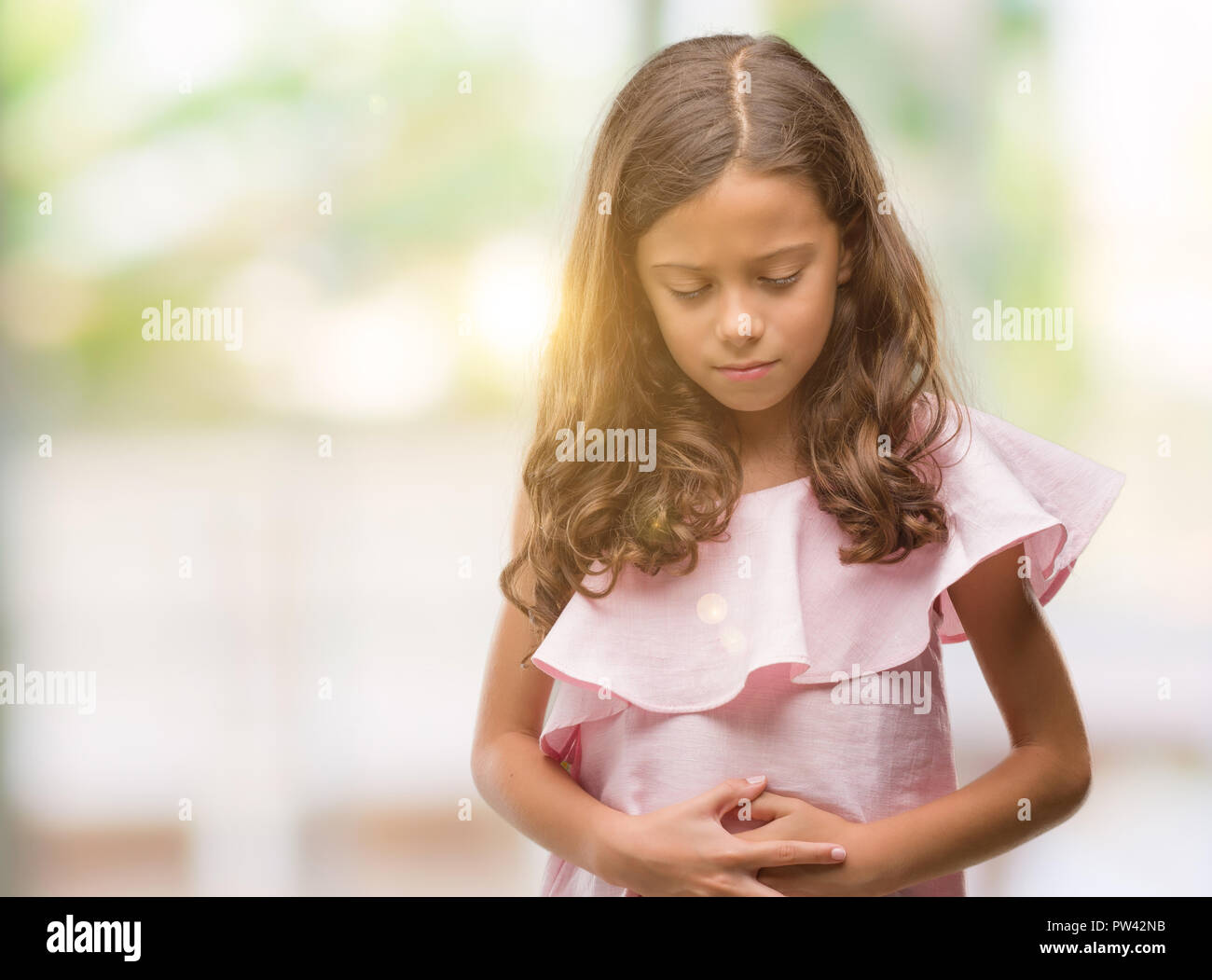 Brunette hispanic girl wearing pink dress with hand on stomach because ...