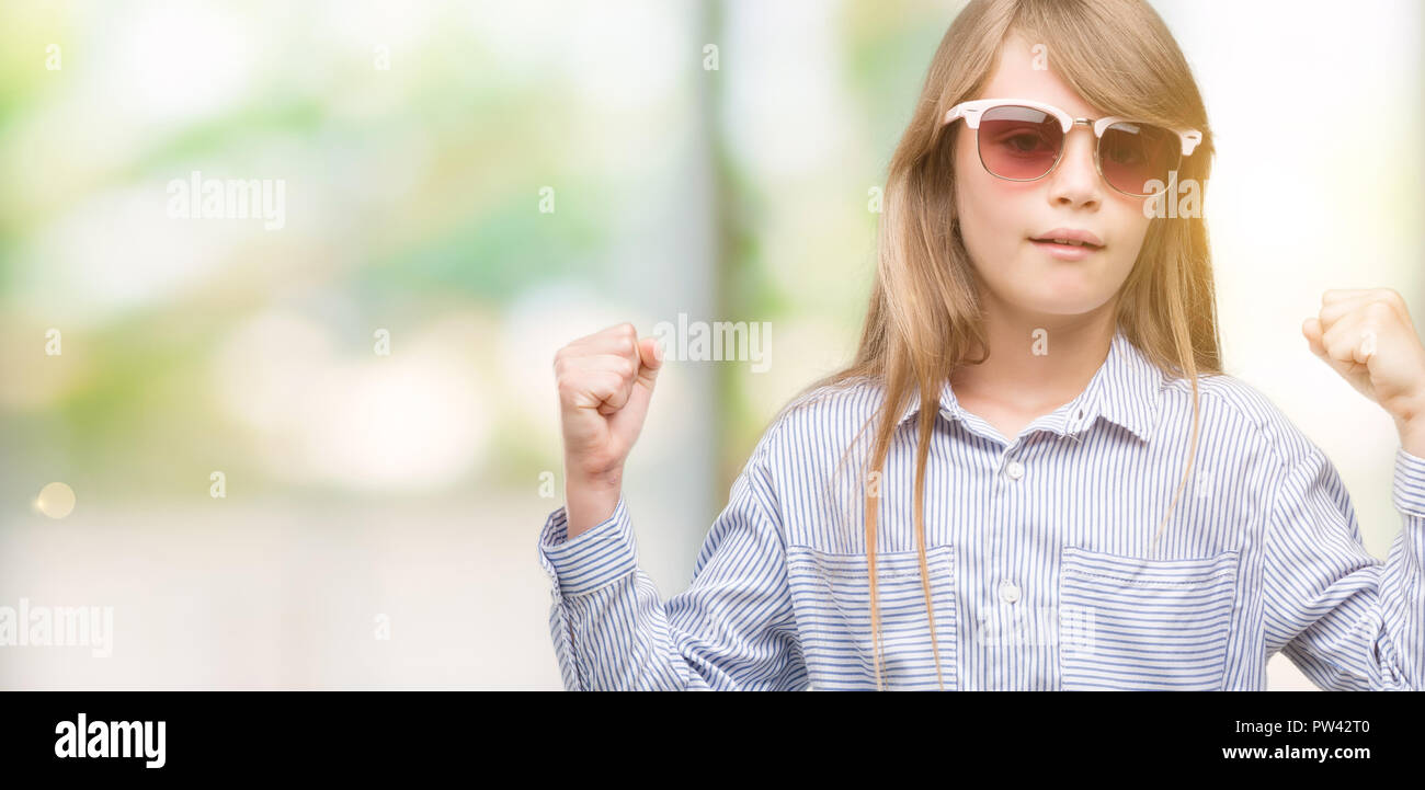 Young blonde toddler wearing blue shirt screaming proud and celebrating ...