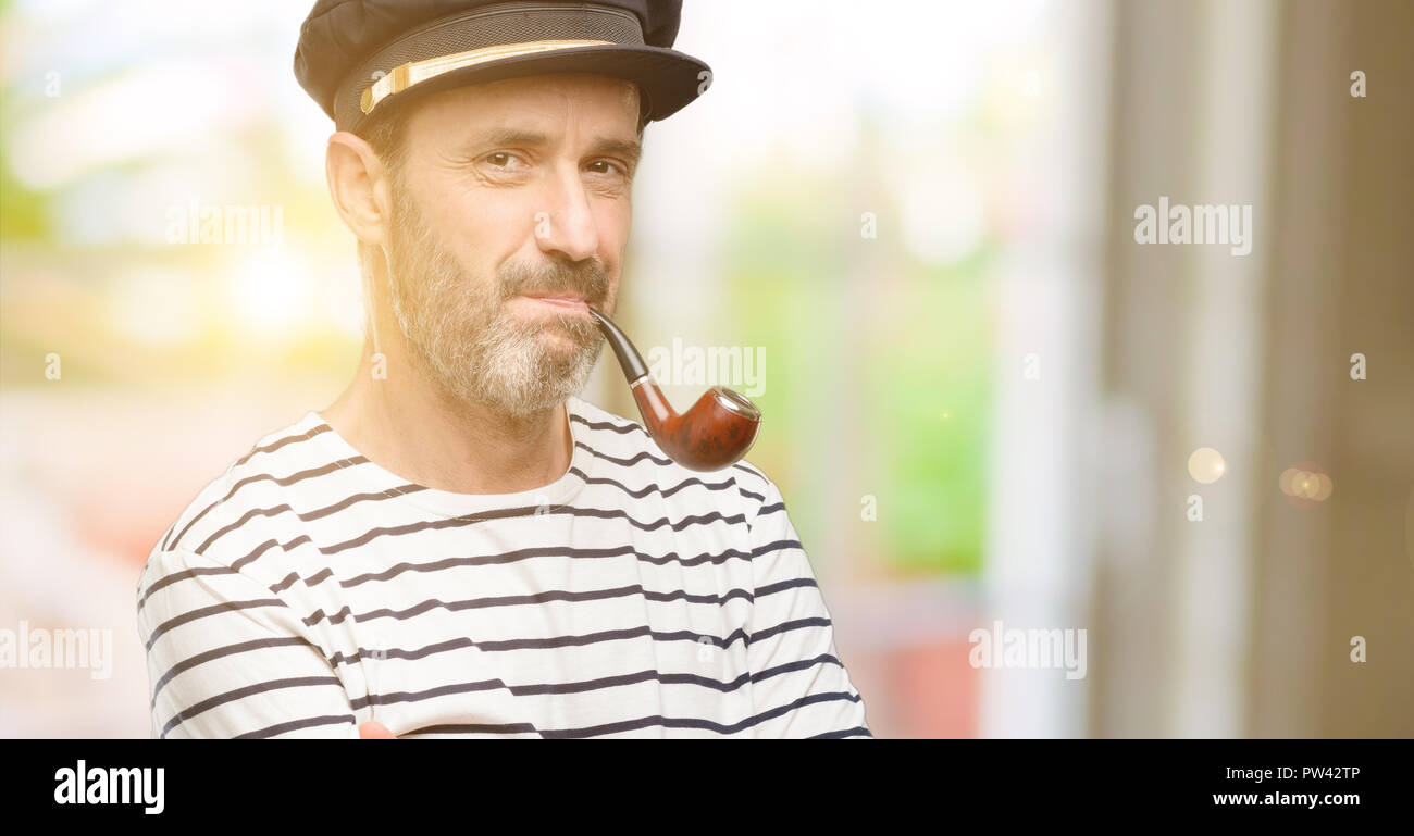 Sailor captain man smoking a tobacco pipe with crossed arms confident ...