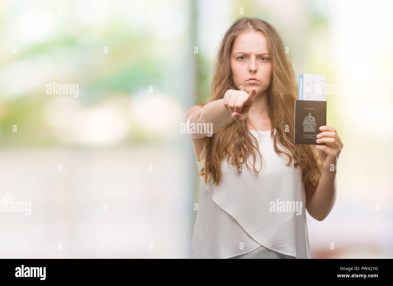 Young blonde woman holding passport of canada and boarding pass ...