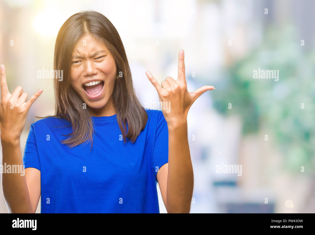 Young asian woman over isolated background shouting with crazy ...